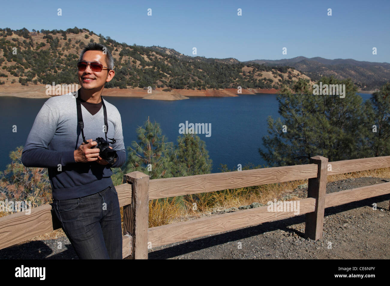 Chinese man standing near lake holding camera Stock Photo - Alamy