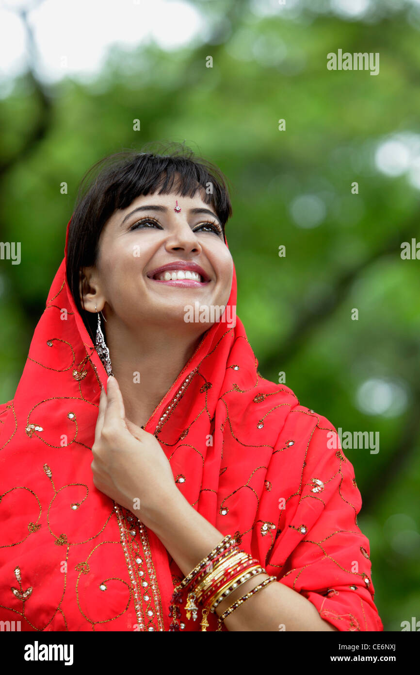 Indian woman looking up and smiling with red sari over her head Stock ...