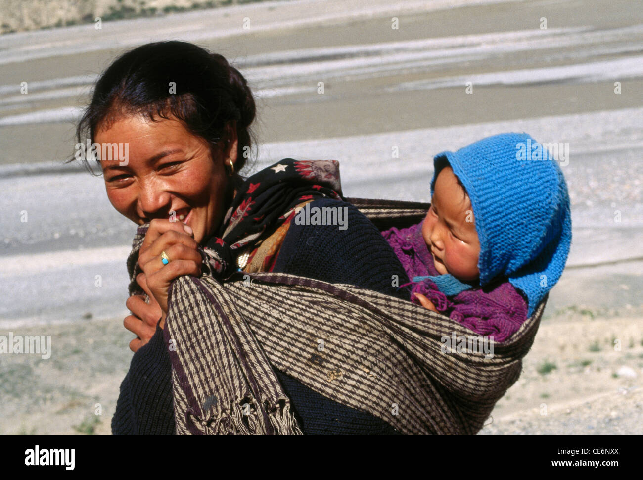 Indian mother carrying baby child piggyback ; Spiti Valley ; Himachal ...
