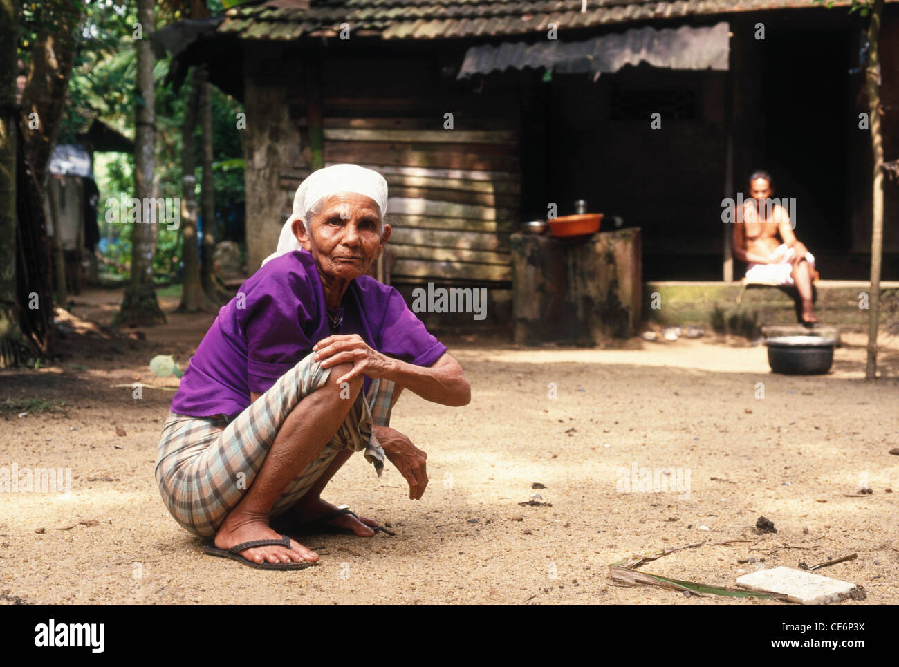 Indian seniors rural woman sitting crouching in front of her house ...
