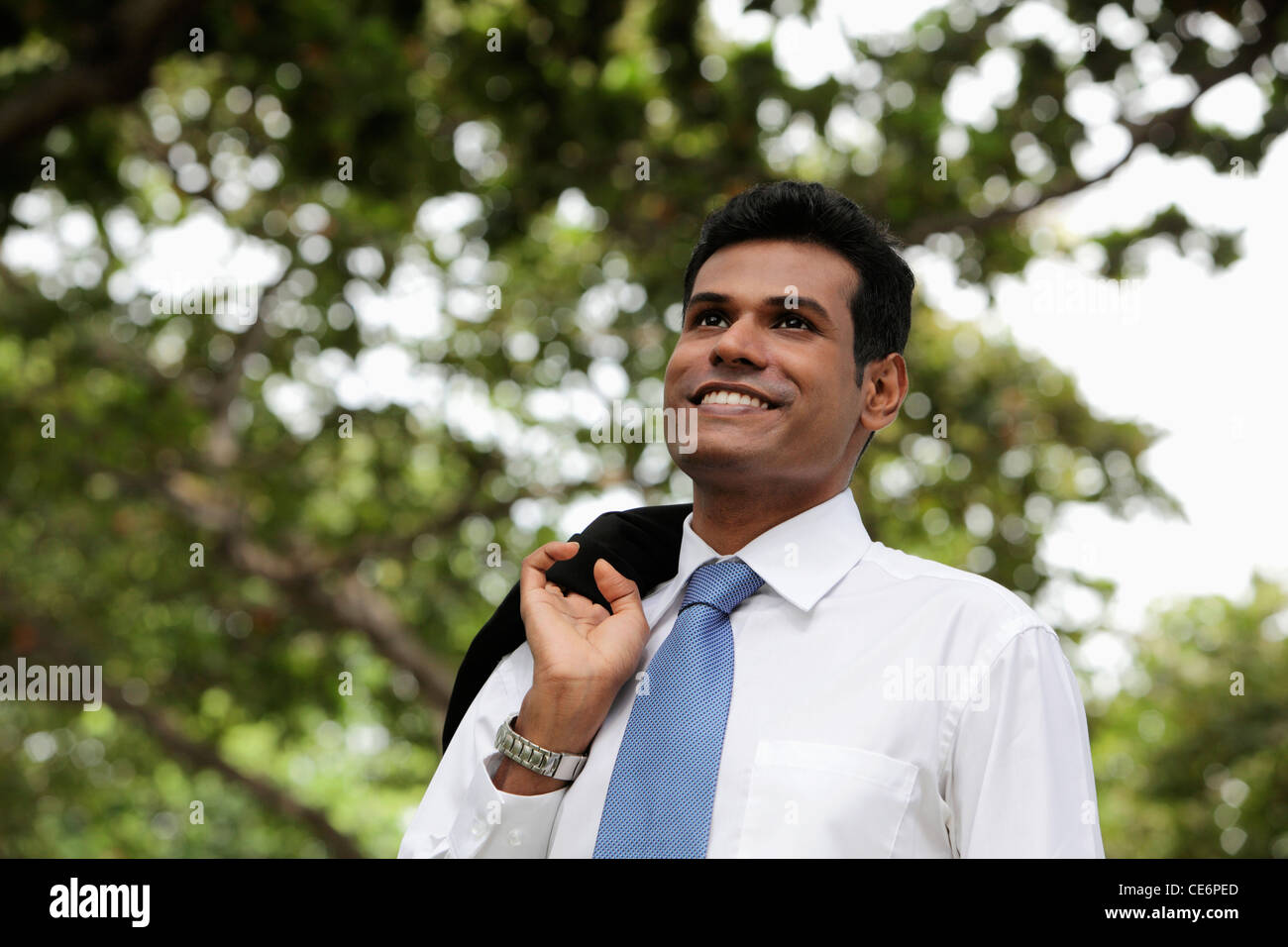 Indian man with coat over his shoulder smiling Stock Photo - Alamy