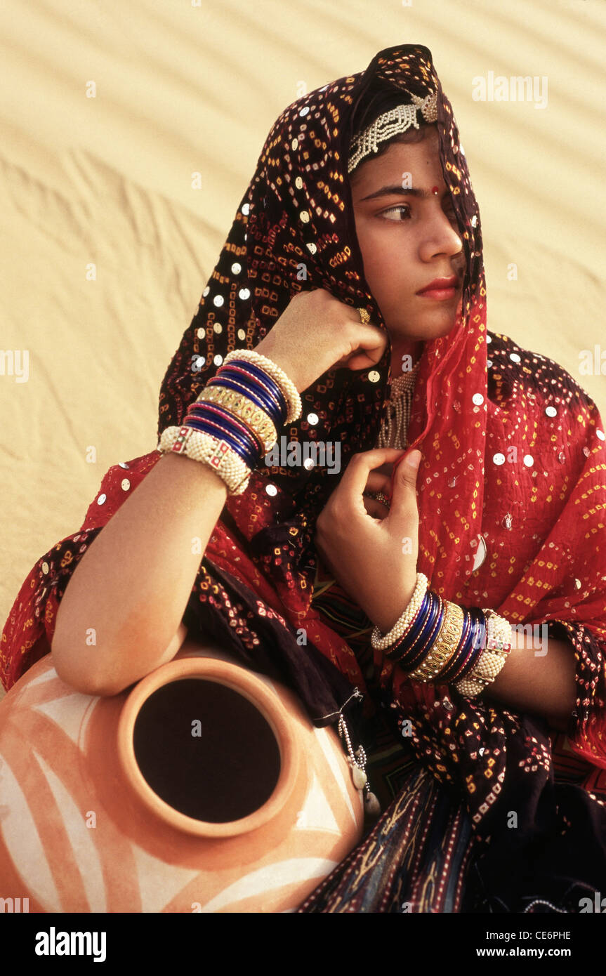 Indian Rajasthani woman in traditional saree sitting on sand dunes with ...