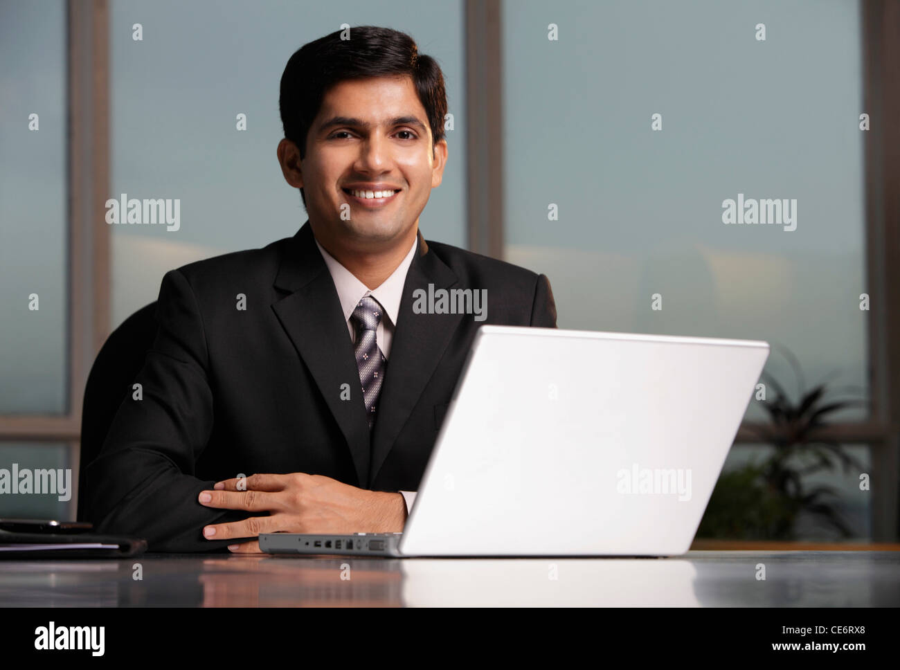 Indian man sitting at table with laptop Stock Photo - Alamy