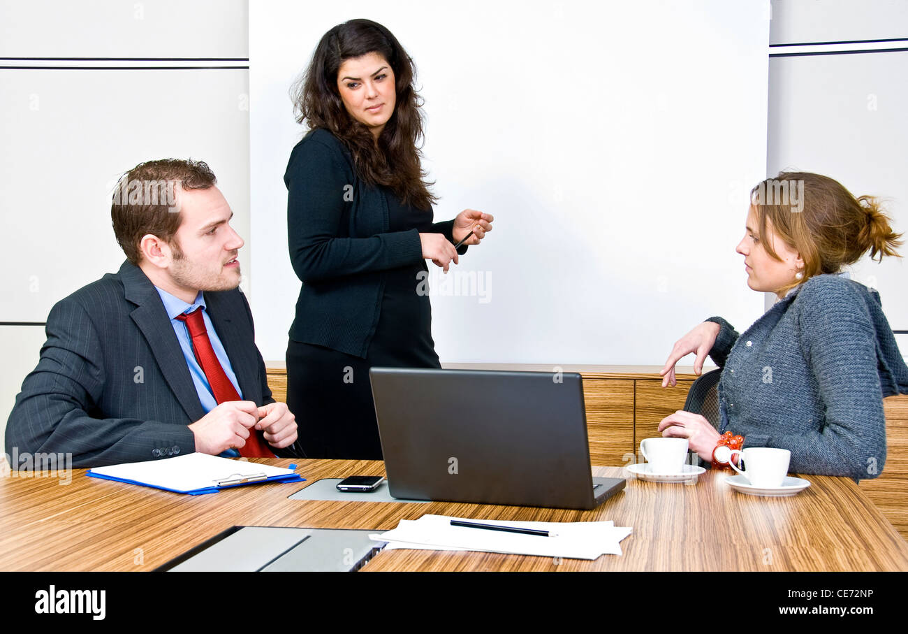 An office scene comprising of staff discussing business matters in ...