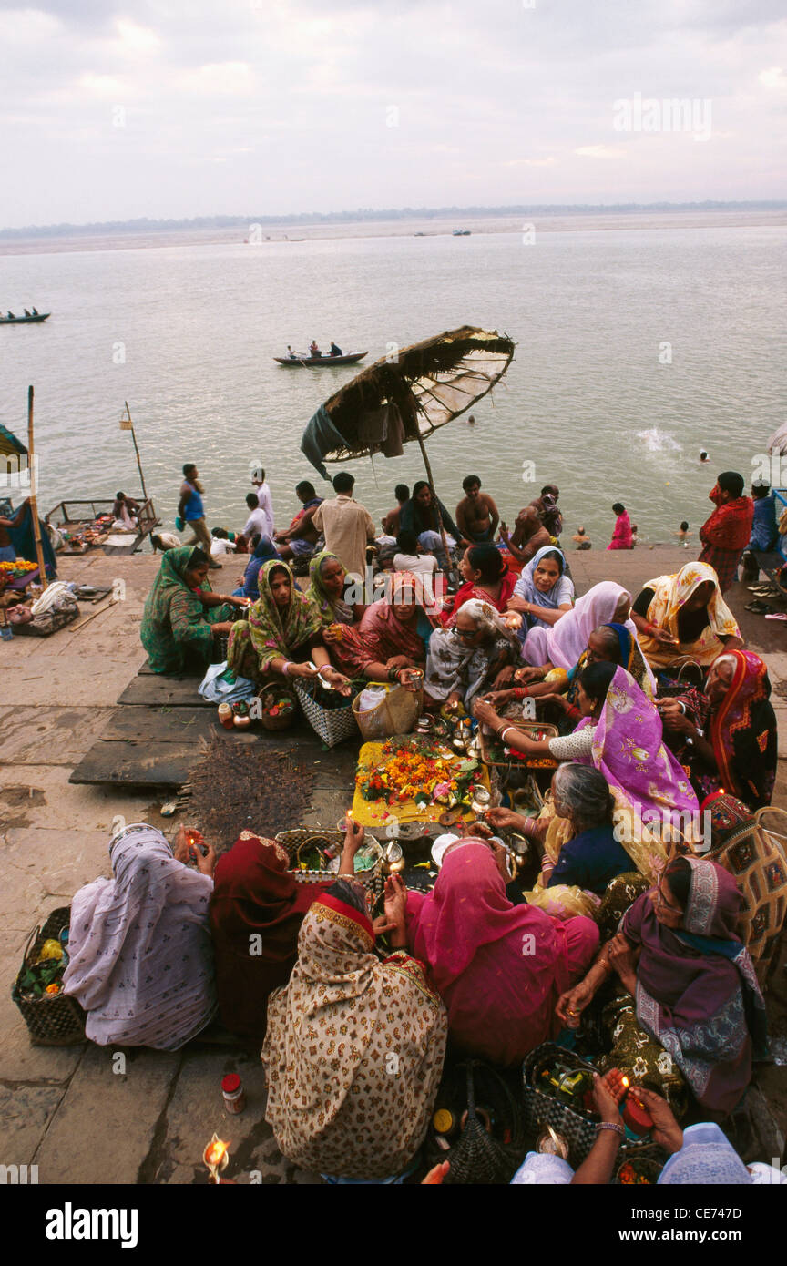 women praying on the steps of the bathing ghat on ganges river ganga ...