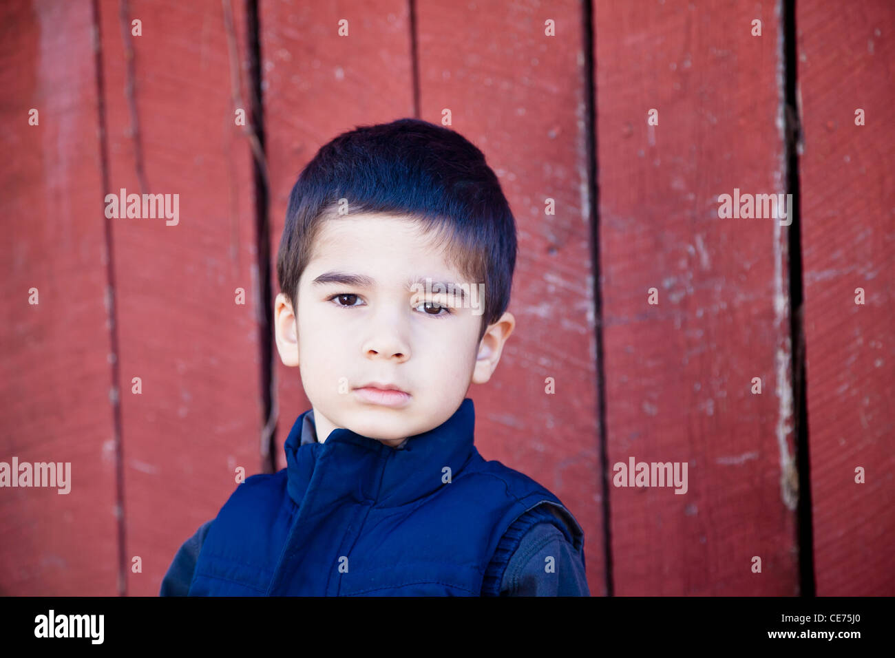 Serious Little Boy Making Eye Contact in front of red textured ...