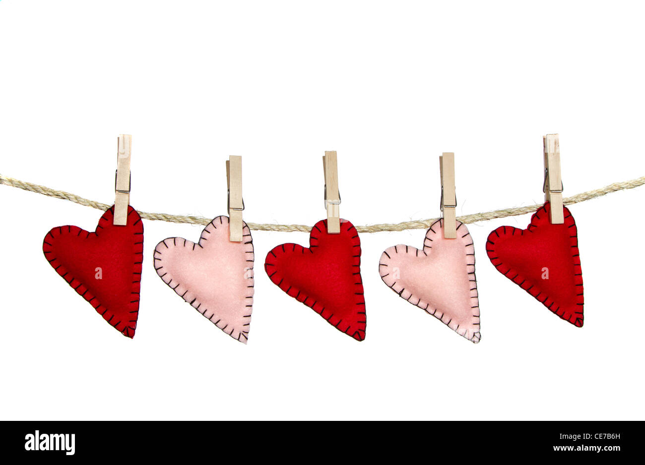 five handmade stitched felt hearts hanging on a clothes line, pink and ...