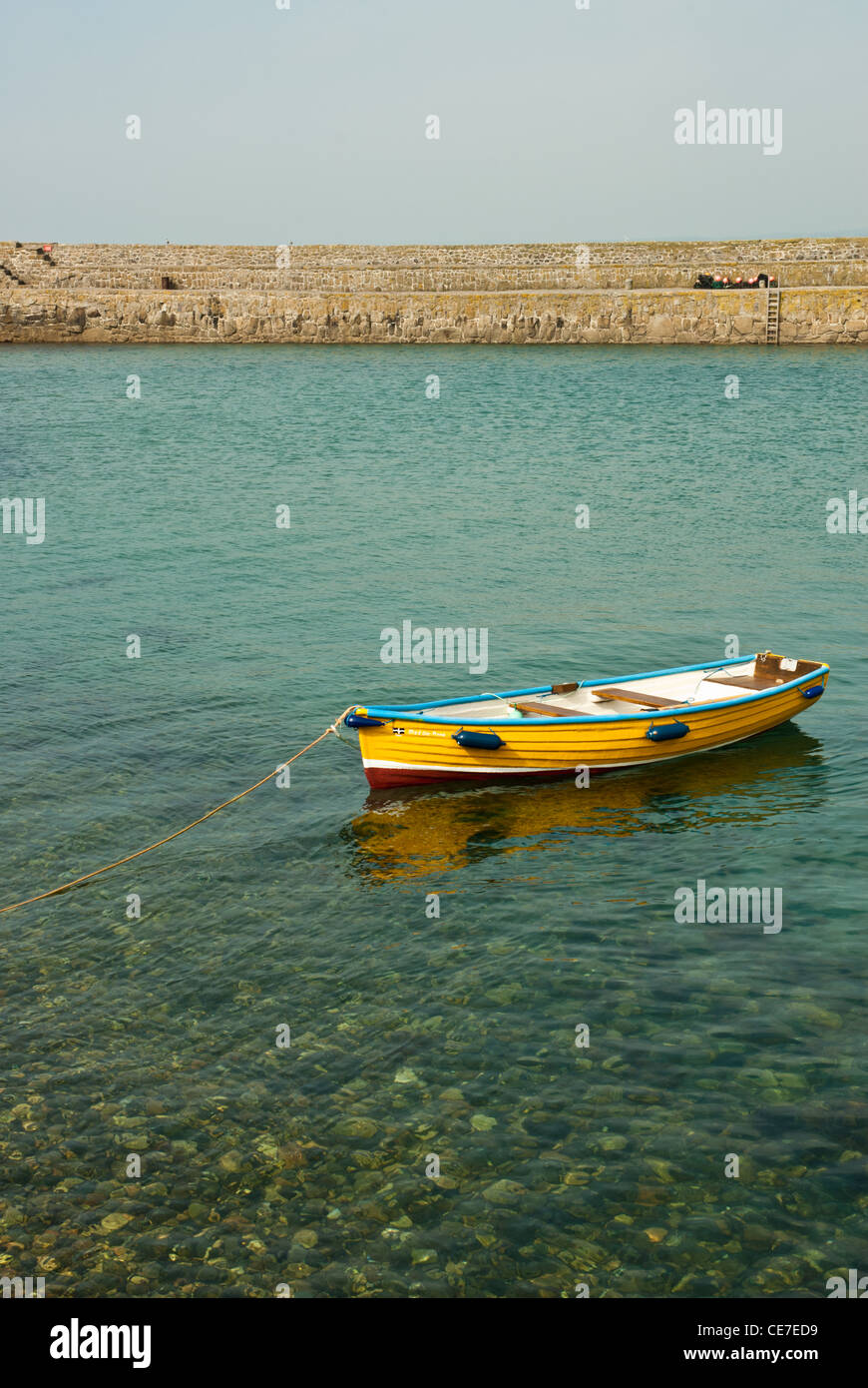 A bright yellow colourful boat in a clear turquoise sea, behind is the ...