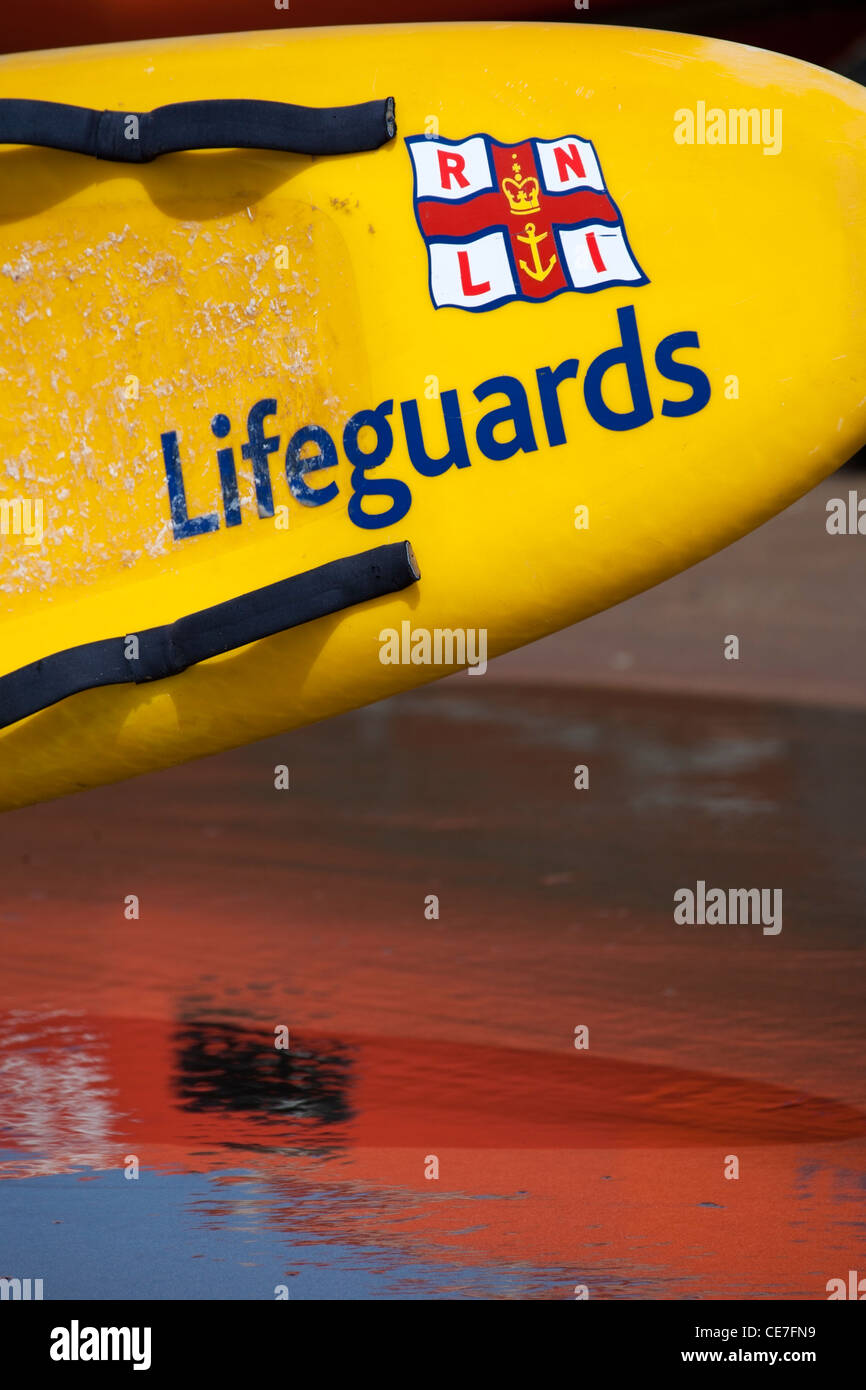 Lifeguards surf board lying on the beach with reflection in the sand ...