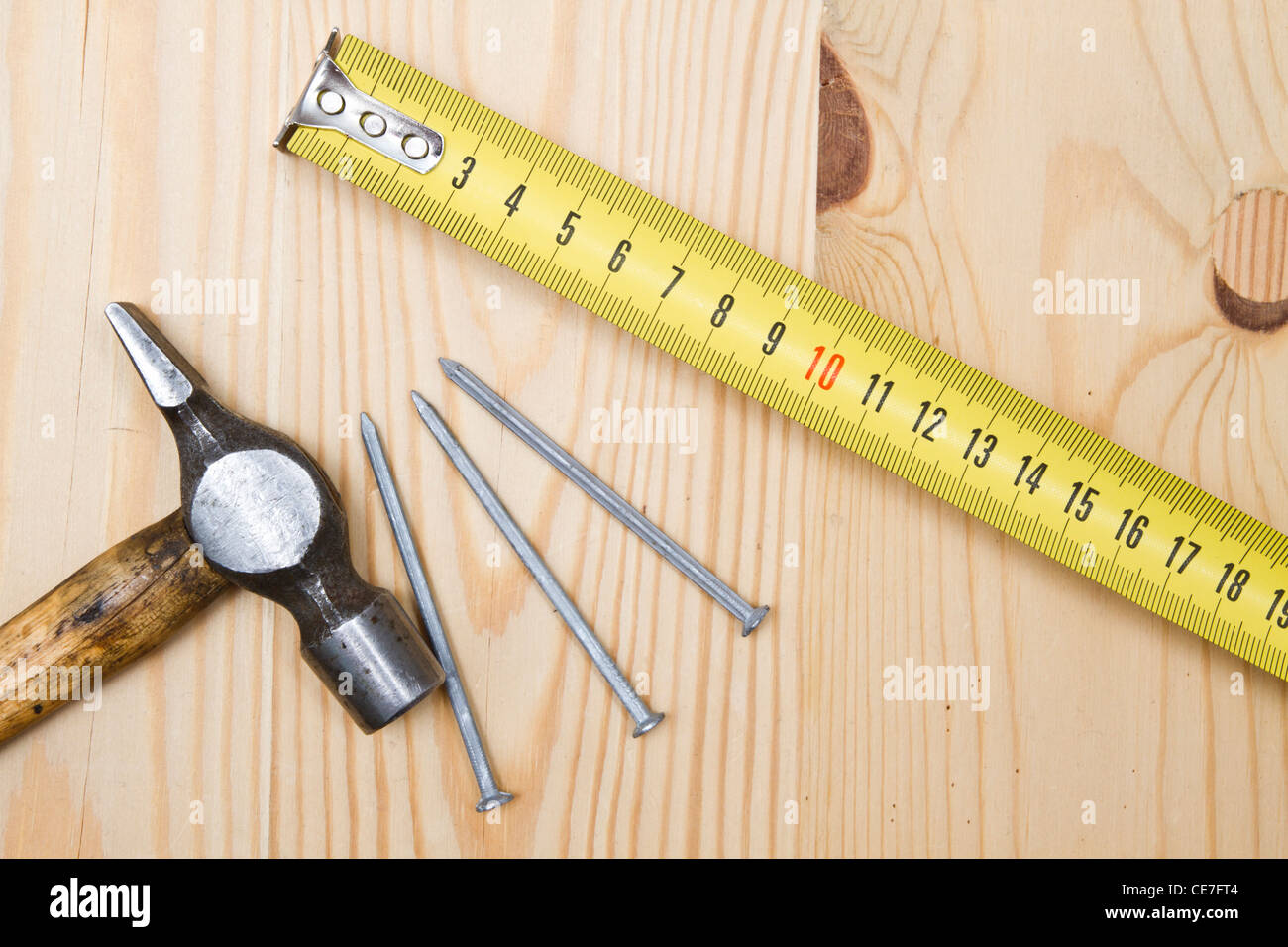 Old hammer , tape measure and nails on wood background Stock Photo - Alamy