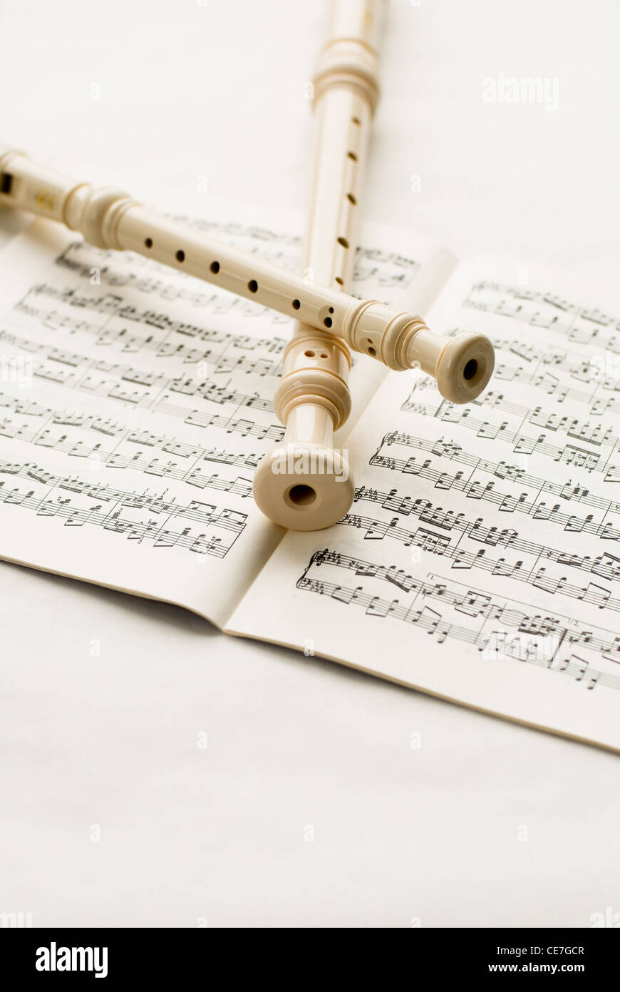 Two block-flutes placed over textbook with musical notes. High key ...
