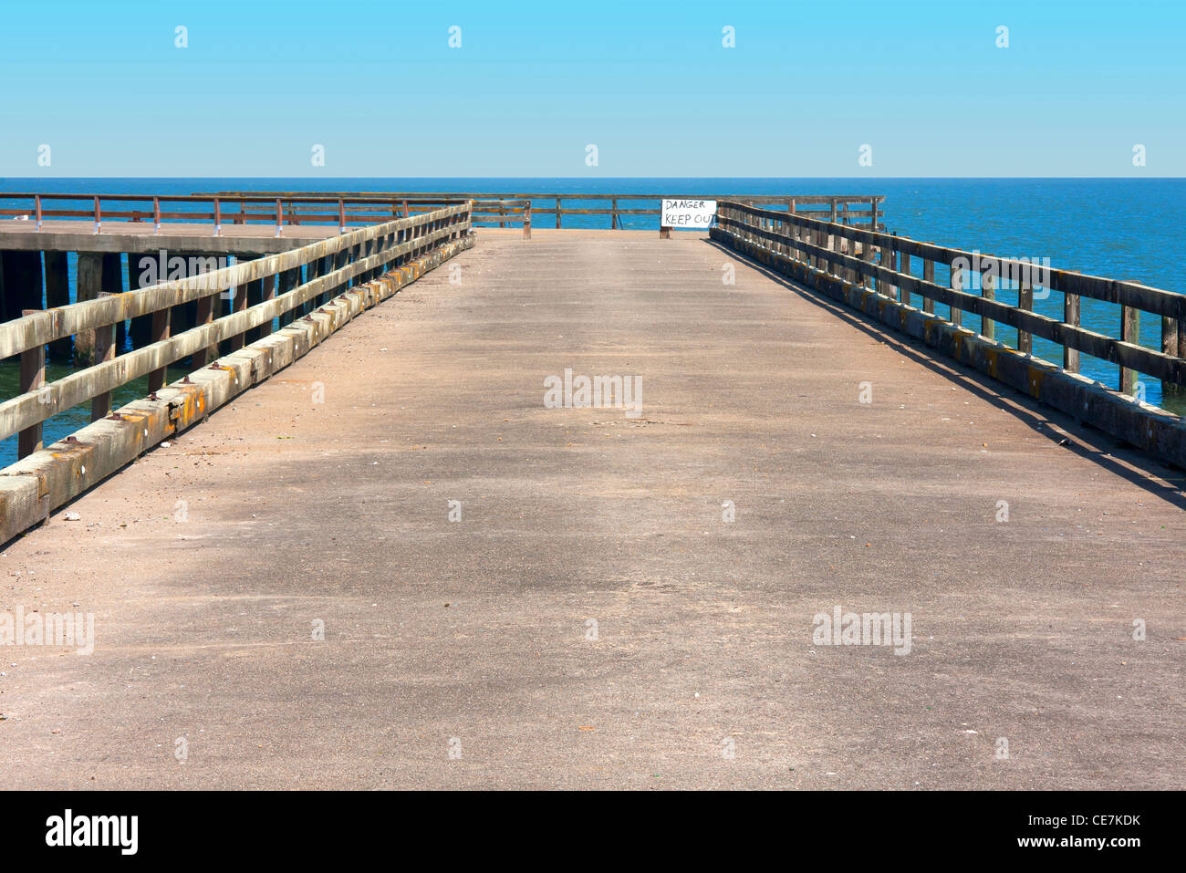 Paved pier to the sea with keep off sign Stock Photo - Alamy