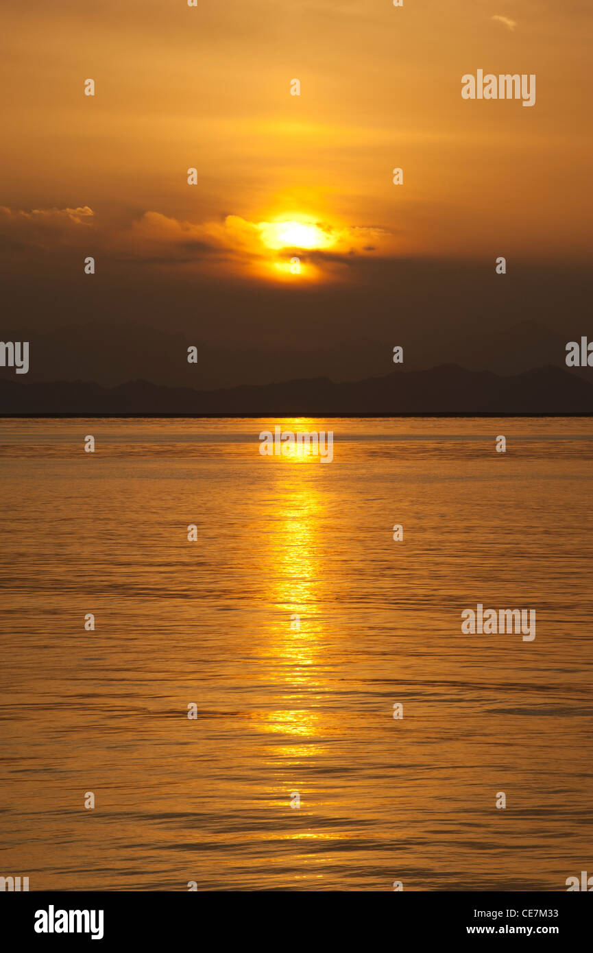 Beautiful sunset with reflection on the water over coastal mountains ...