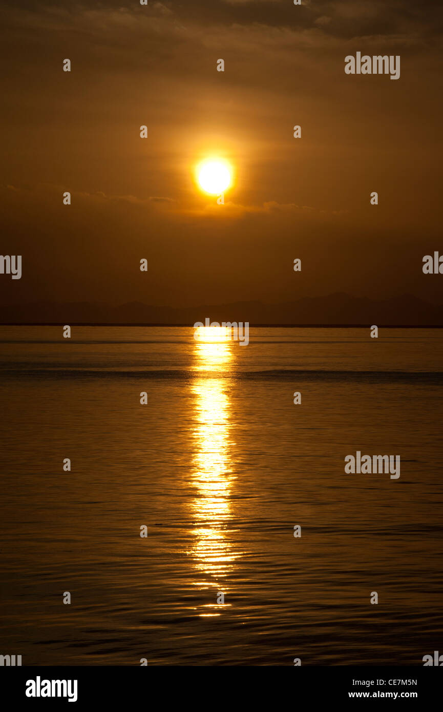Beautiful sunset with reflection on the water over coastal mountains ...