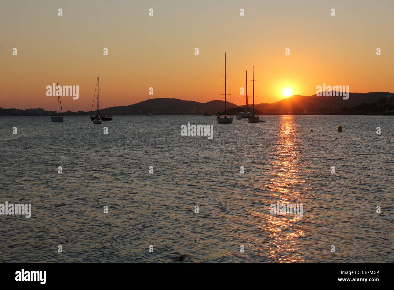 Coastal scene at evening - sailing yachts at anchor in setting sun with ...