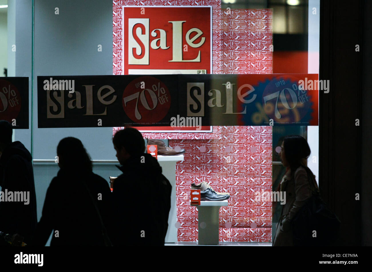 sale signs in a shop window with people looking through the window ...