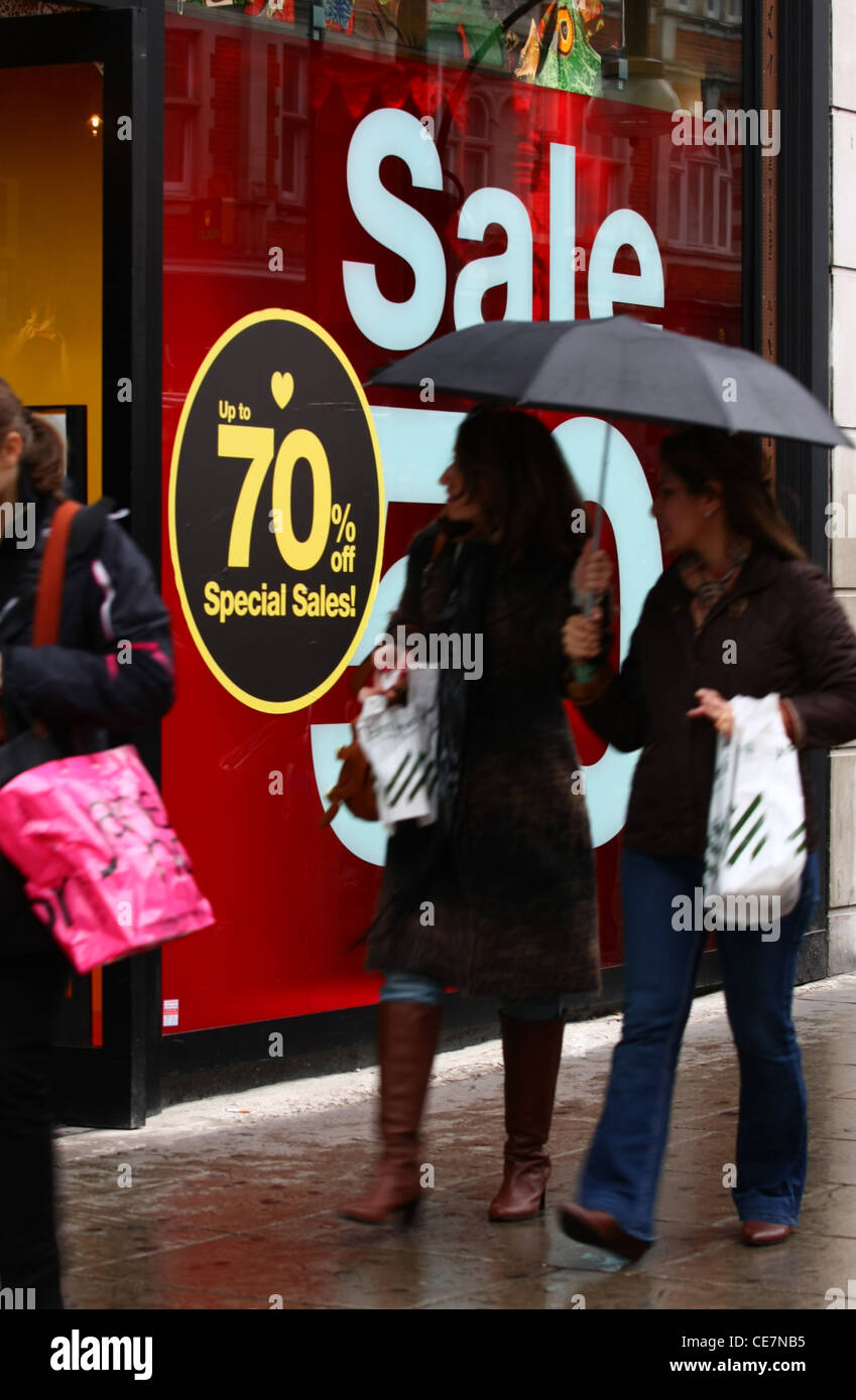 sale sign in a shop with people walking passed Stock Photo - Alamy