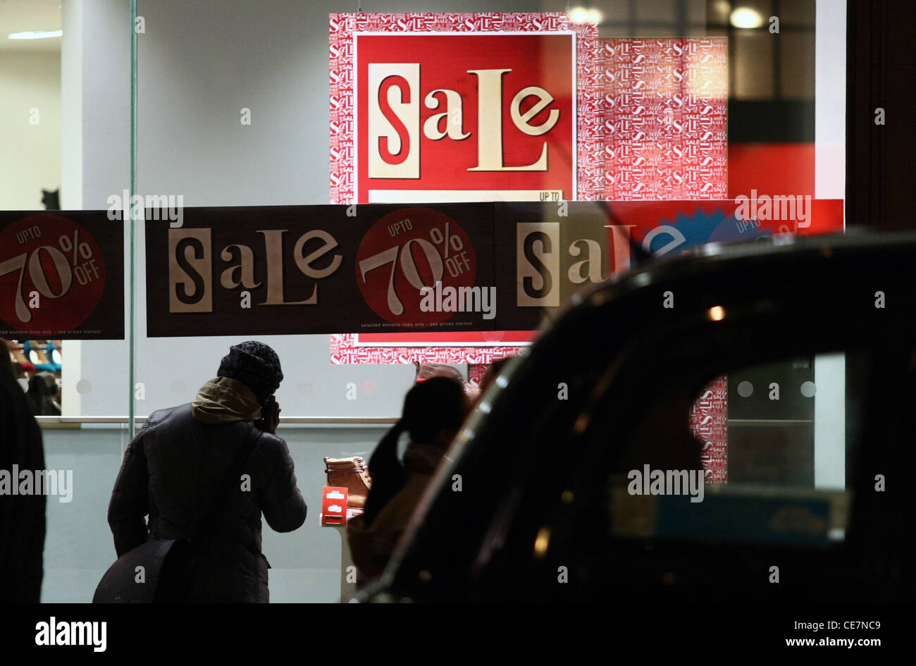 sale signs in a shop window with a vehicles passing and people looking ...