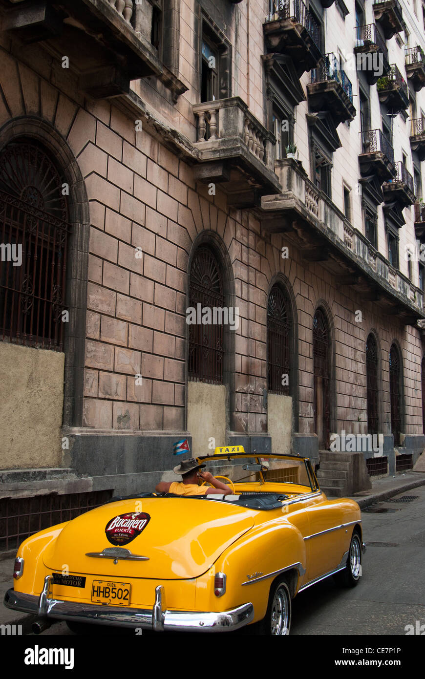 old American car used as taxi with a driver on his mobile phone wearing ...