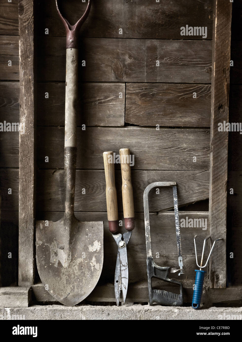 gardening tools leaning against a barn wood wall Stock Photo - Alamy