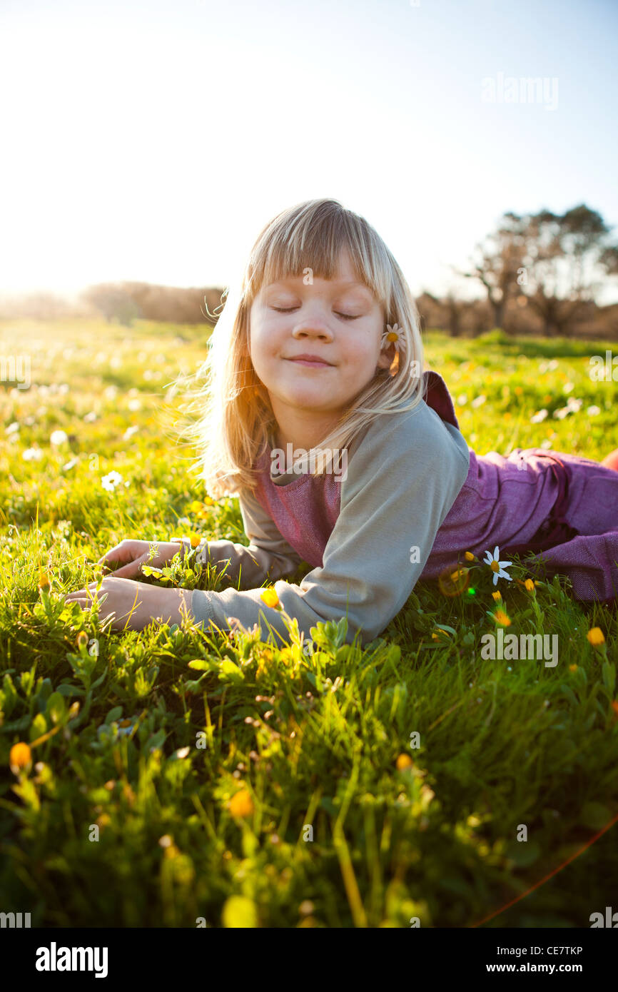 Cute little girl outdoors on a green field with flowers Stock Photo - Alamy