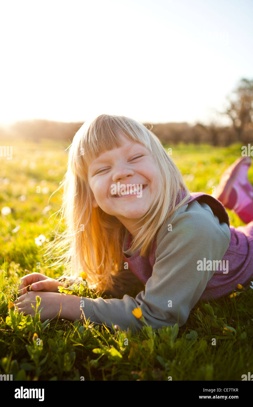 Cute little girl outdoors on a green field with flowers Stock Photo - Alamy