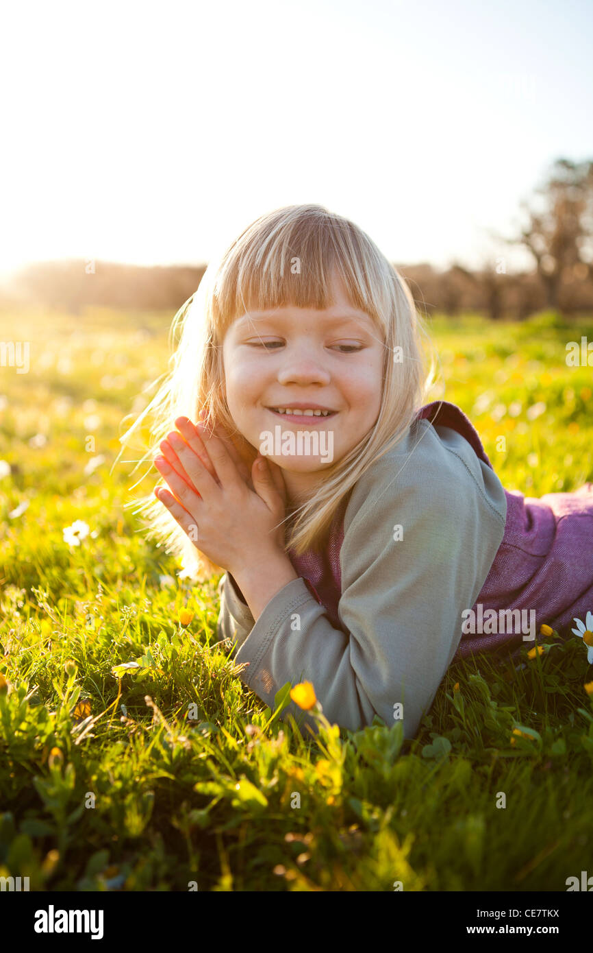 Cute little girl outdoors on a green field with flowers Stock Photo - Alamy
