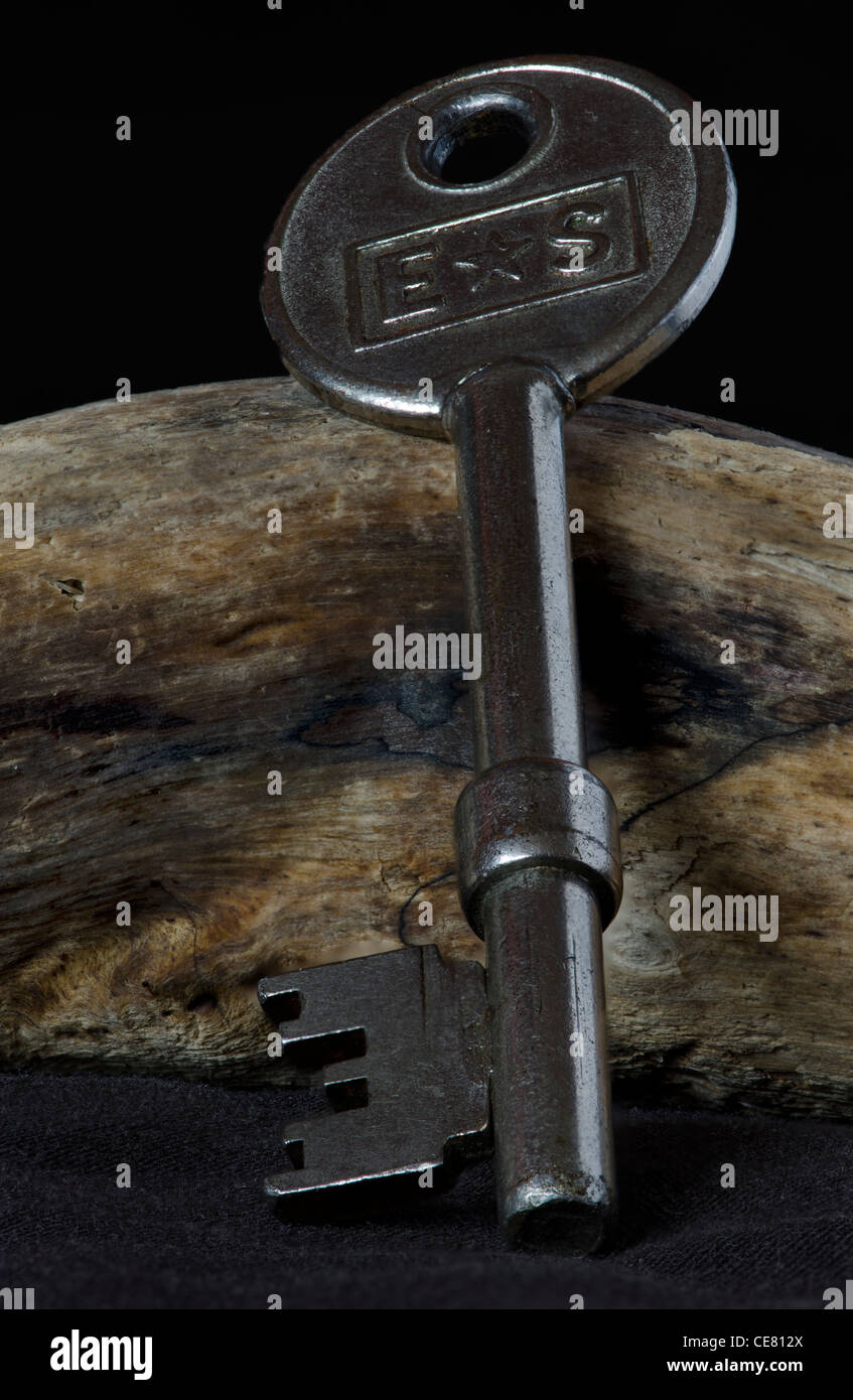 Door lock key on supported by a bit of drift wood Stock Photo - Alamy