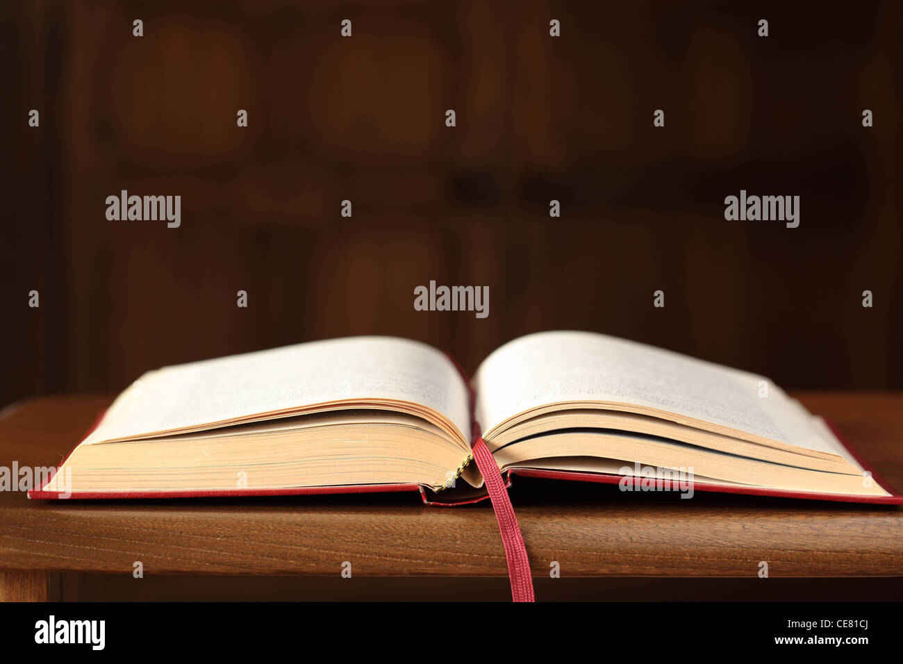 Close up of an open red book on an oak table with blurred background ...