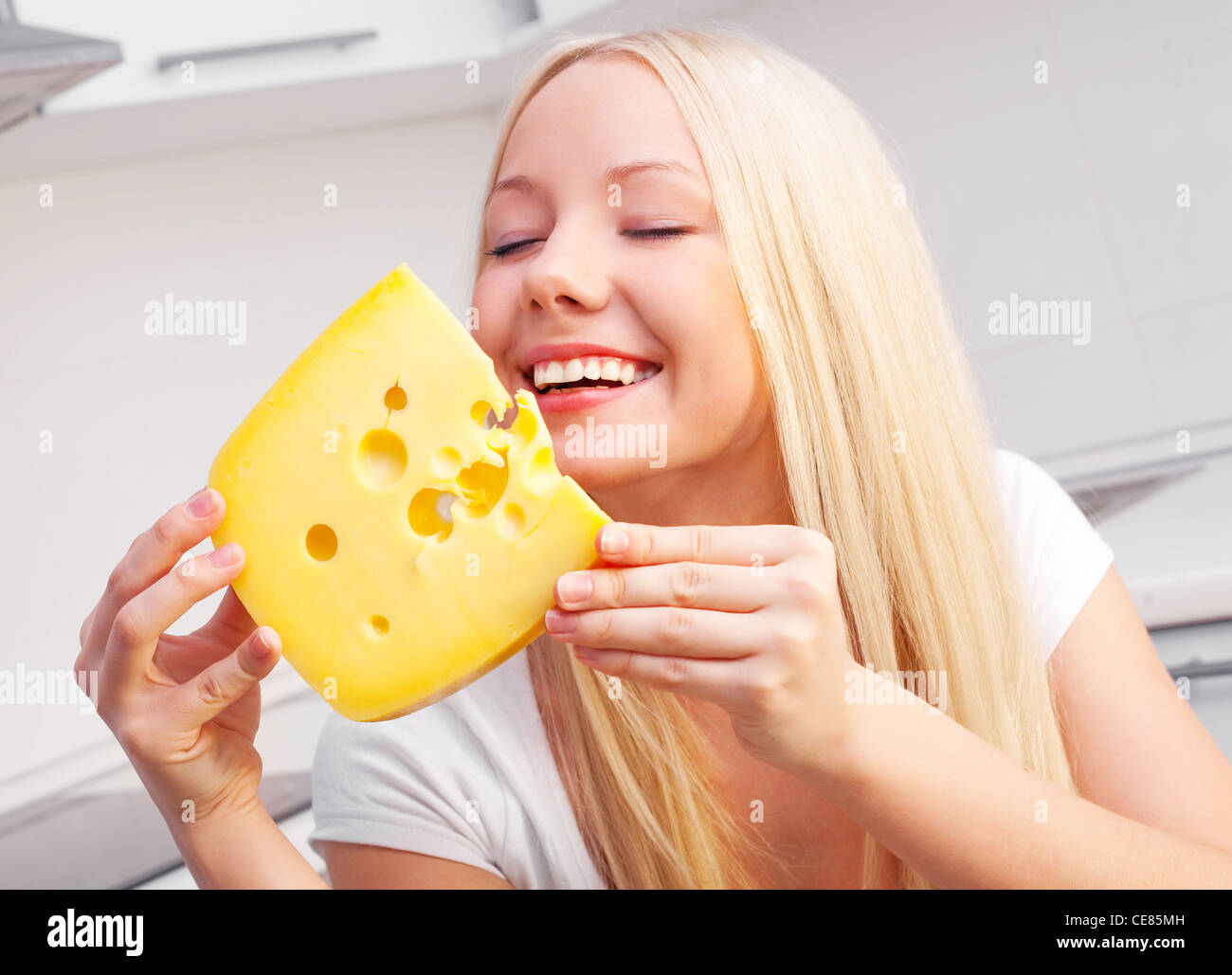 beautiful young blond woman with cheese in the kitchen at home Stock ...