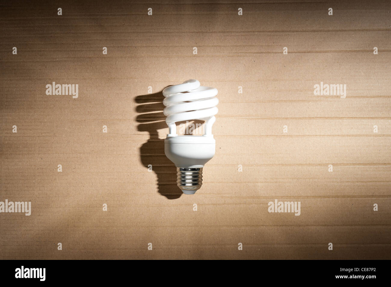 white fluorescent light bulb with strong shadow against cardboard ...