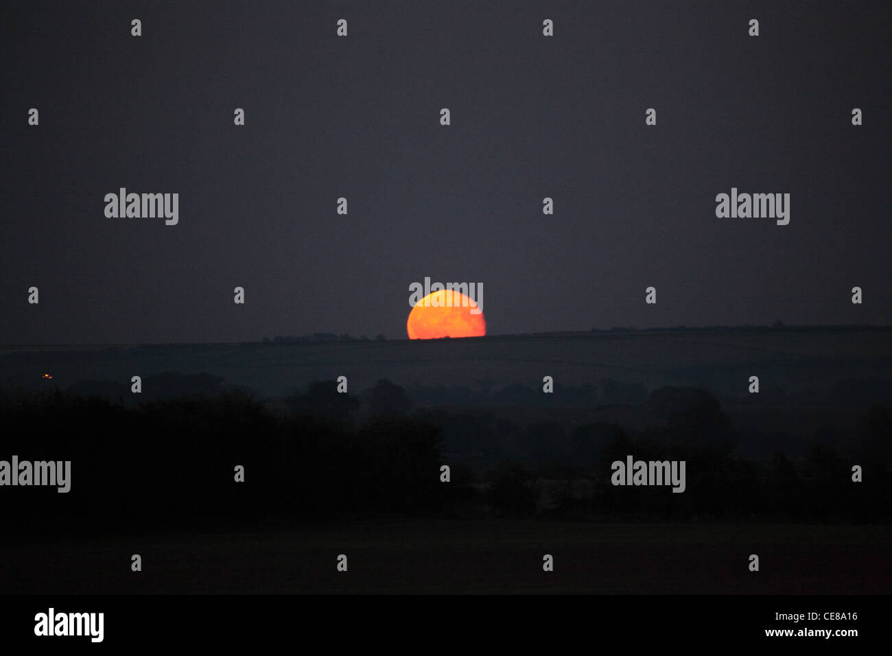 nearly full moon rising over horizon in the early evening light Stock ...
