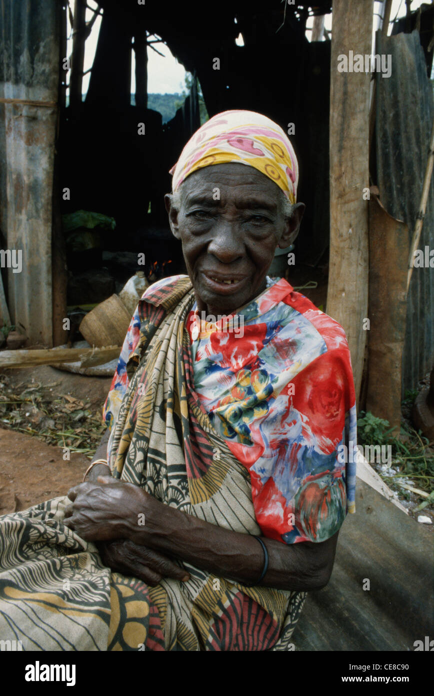 Elderly woman sitting by her home made from corrugated iron, Rwanda ...