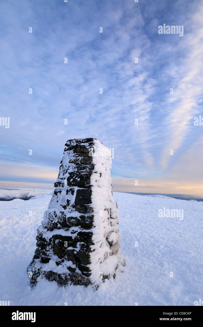 Helvellyn summit trig point clad in snow under dramatic cloudy skies ...