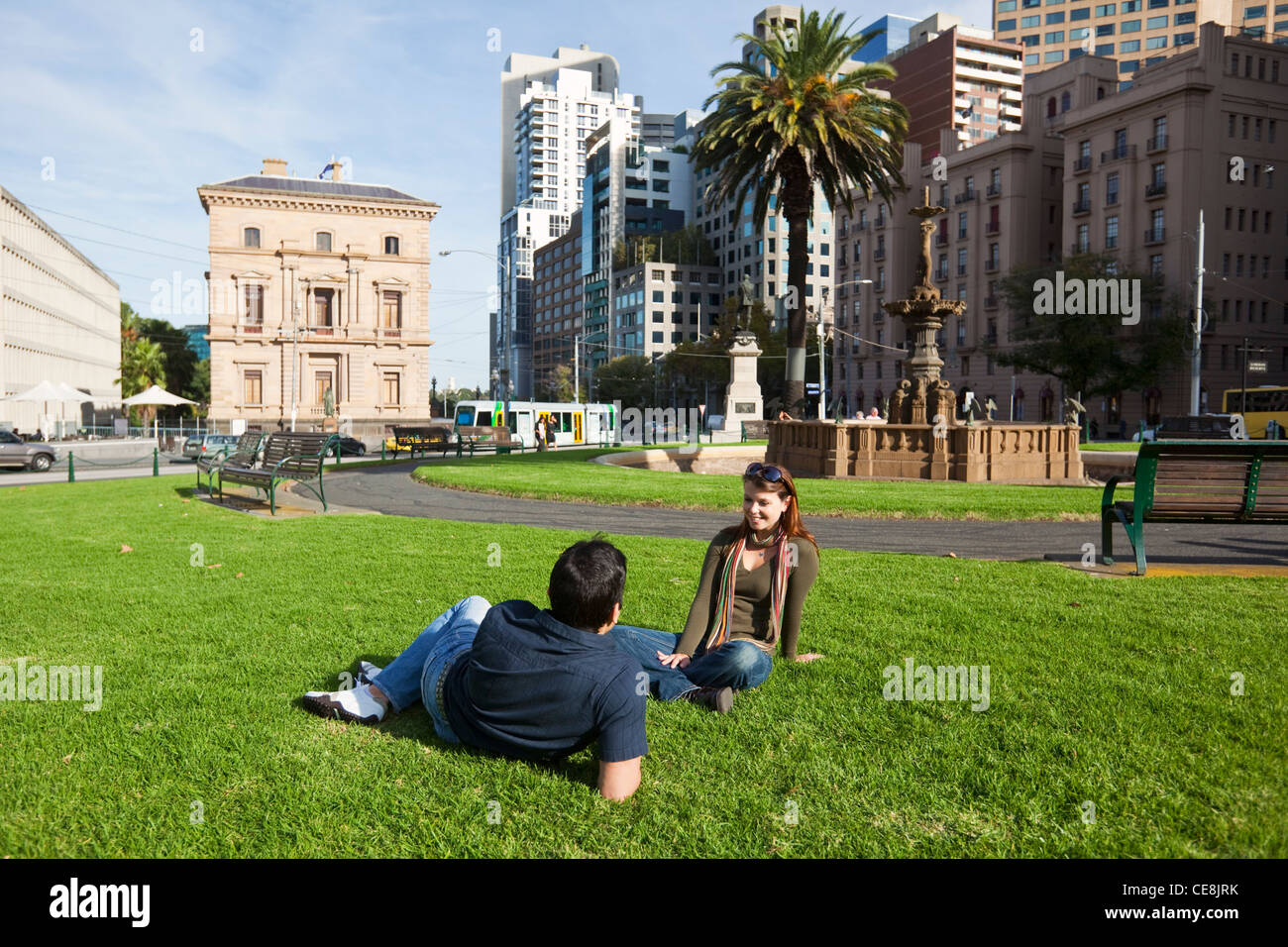 Young couple relaxing in park with city skyline in background. Gordon ...