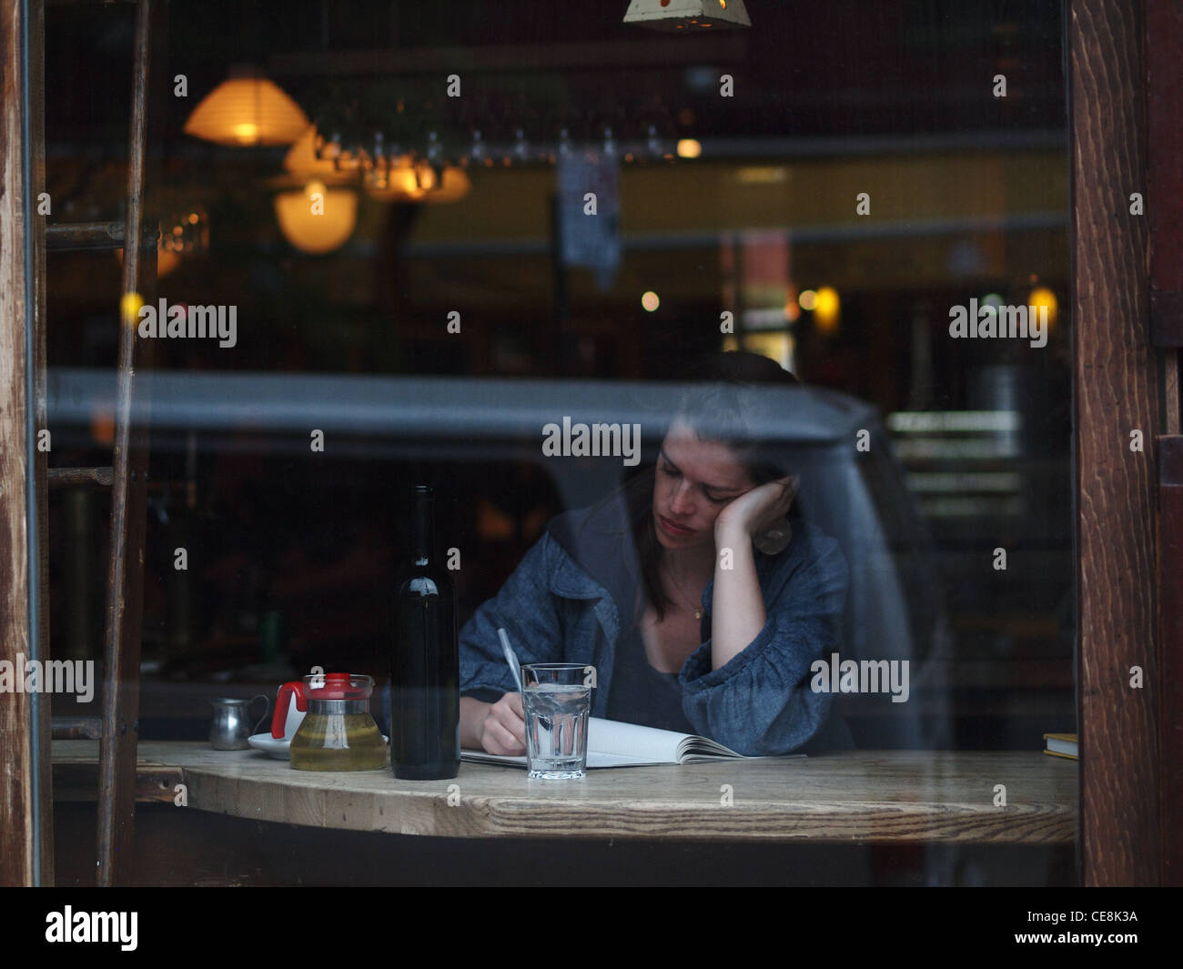 Woman in coffee shop window writing, Brooklyn, New York Stock Photo - Alamy