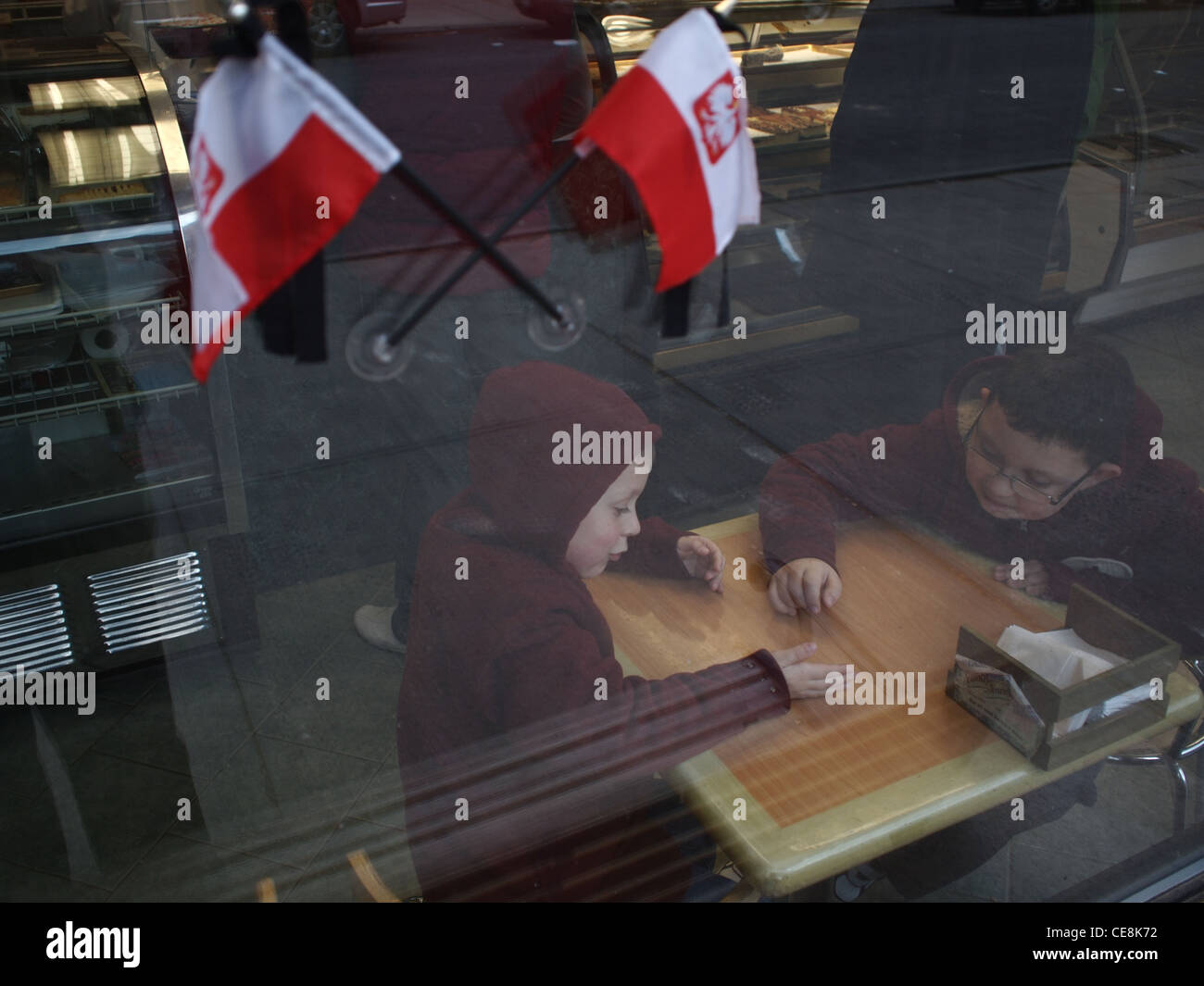 Two boys playing in Polish bakery with Polish flags in window, Brooklyn ...