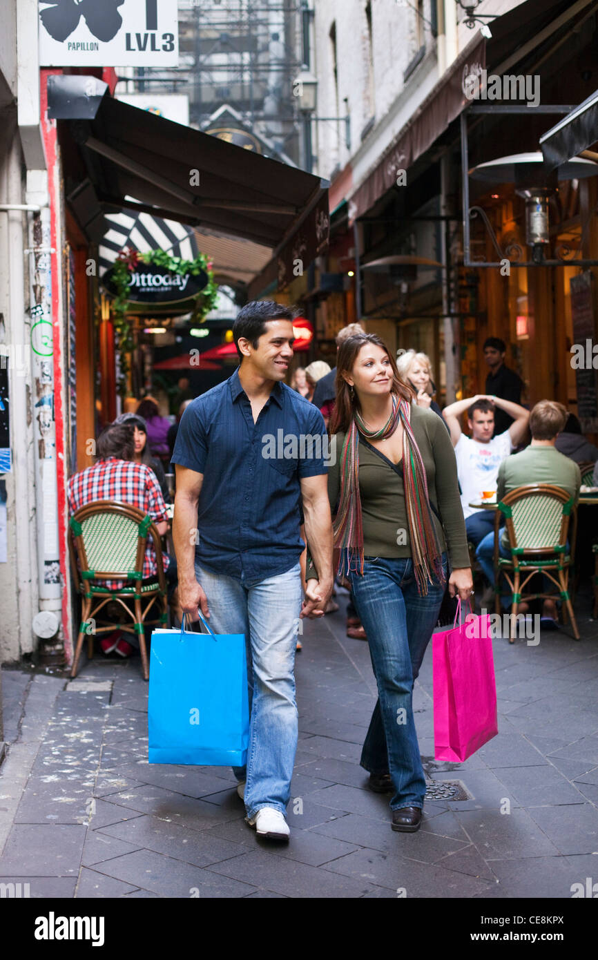 Couple with shopping bags walking past laneway cafes. Melbourne ...