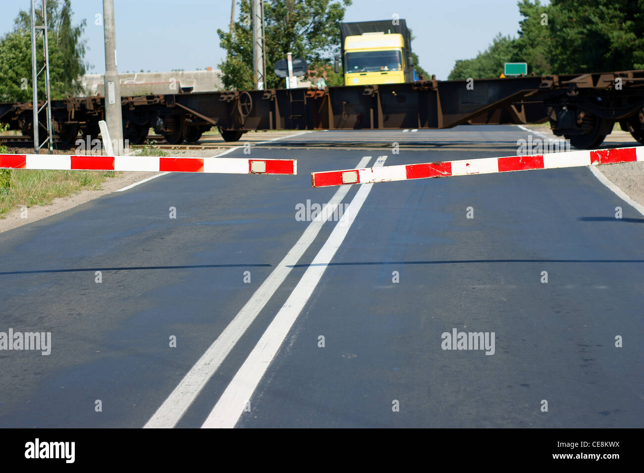 Freight train passing a railroad crossing with gates Stock Photo - Alamy