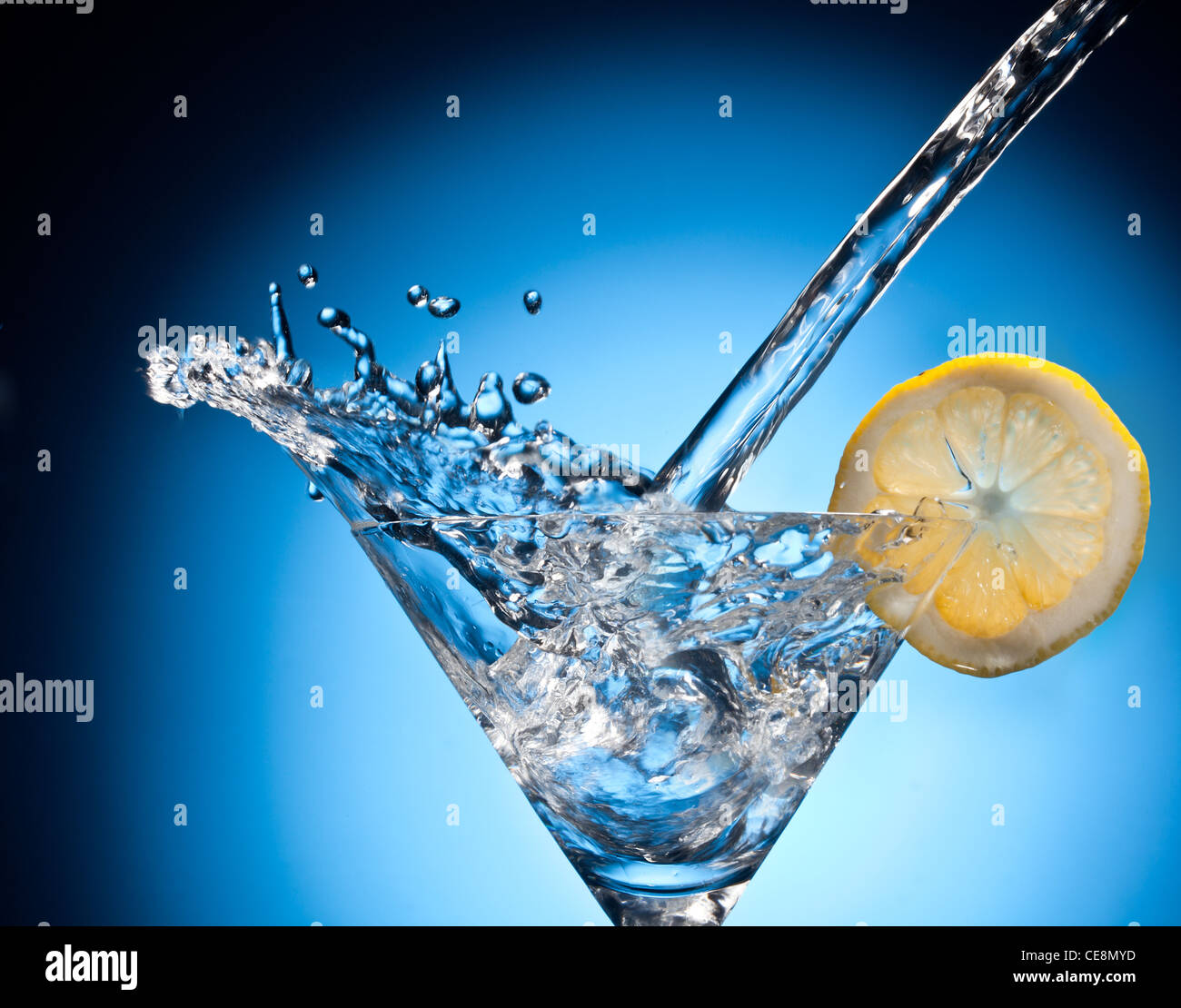 Splash from pouring martini into the glass. Object on a blue background ...