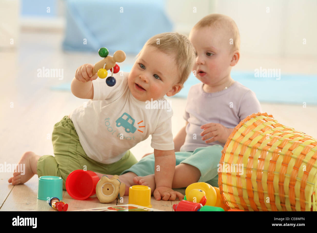 Two babies playing on the floor Stock Photo - Alamy