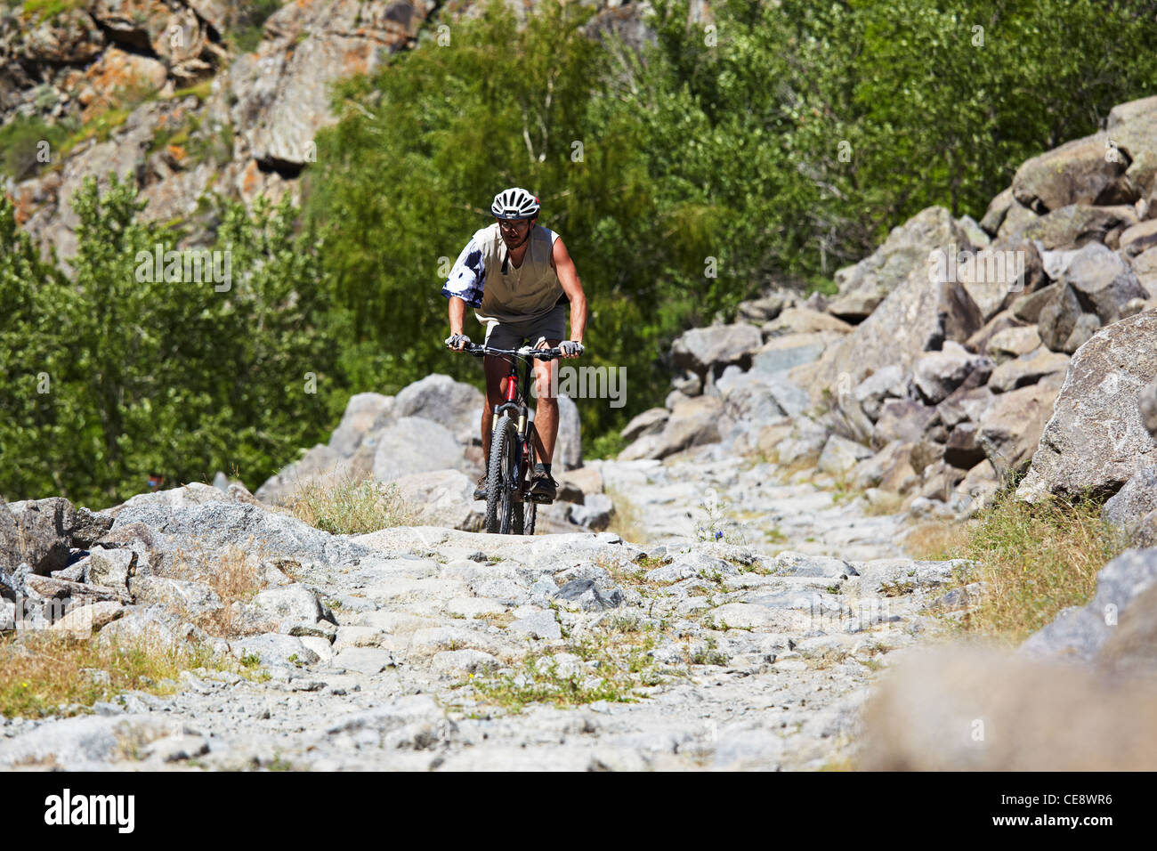 Biker on the old stone road in the rocky mountains Stock Photo - Alamy