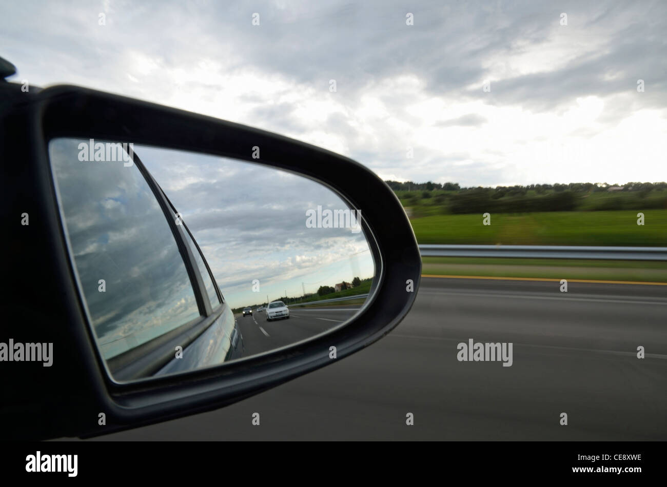Rear-view mirror from a speeding car on highway, France (blurred motion ...