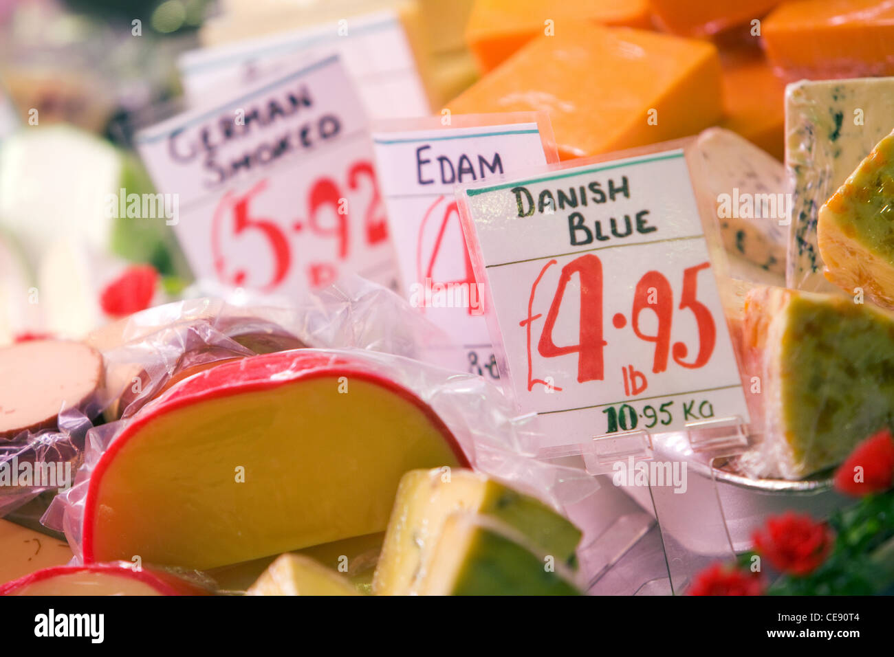 Various types of cheese on display on a stall in an indoor food market ...