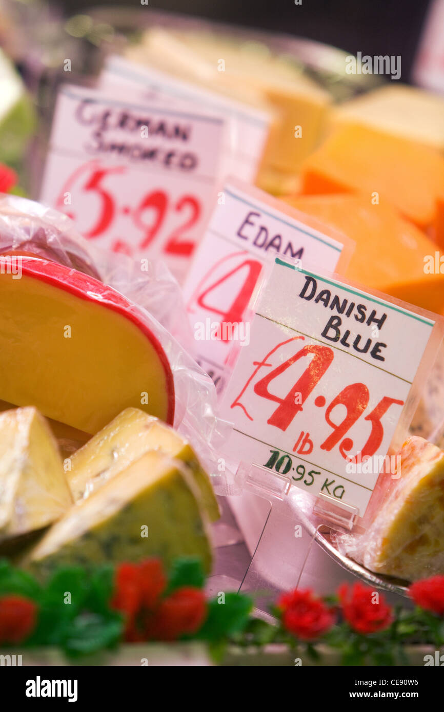 Various types of cheese on display on a stall in an indoor food market ...