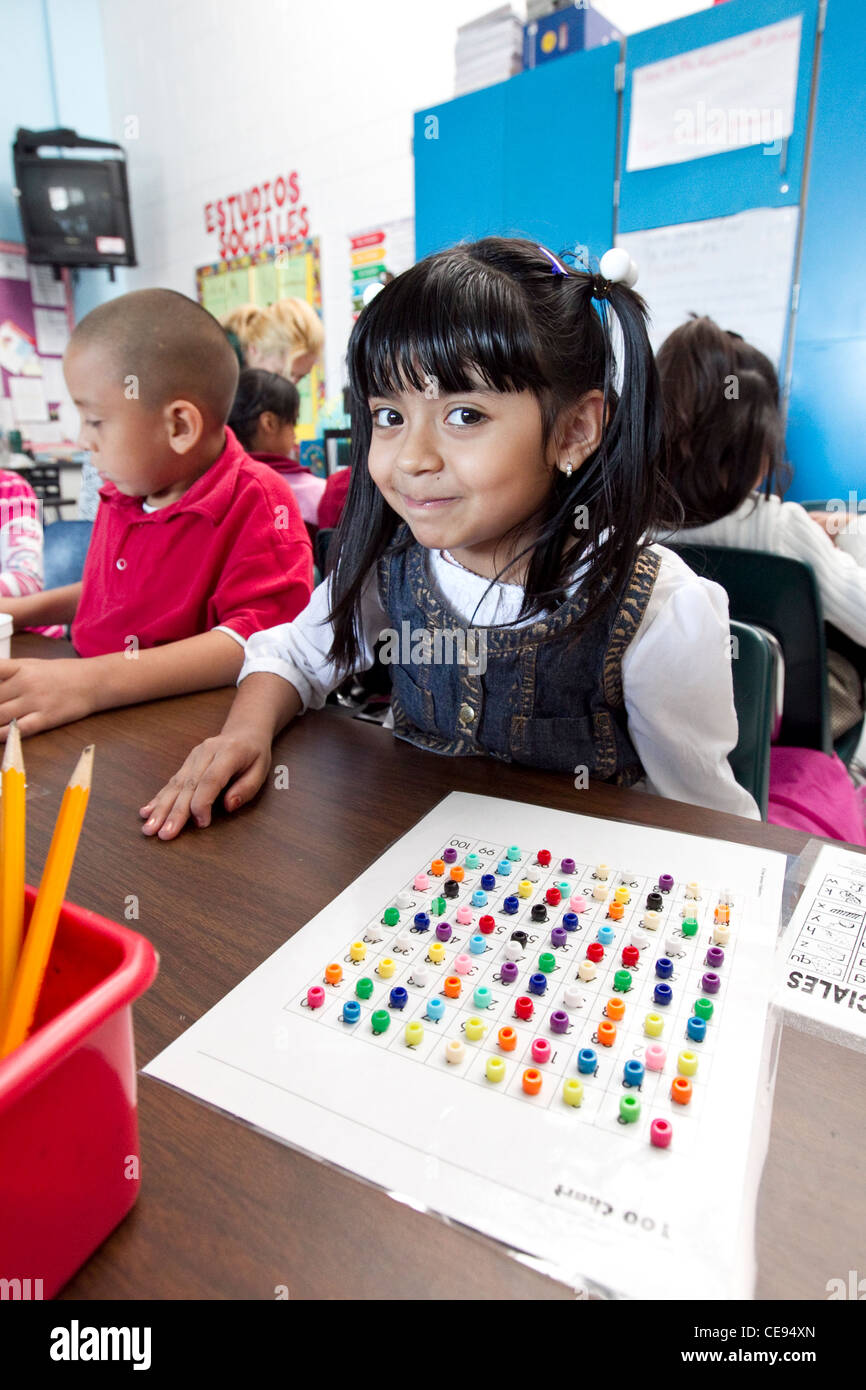 Young female Hispanic elementary age student smiles in classroom after ...
