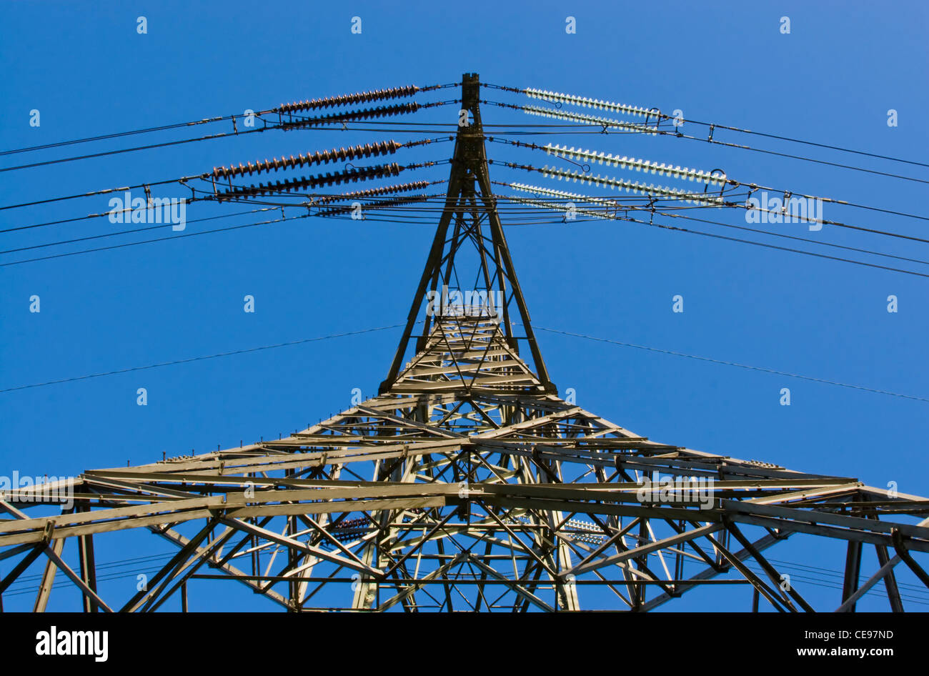 Close up vertical view of an electricity pylon against a clear blue sky ...