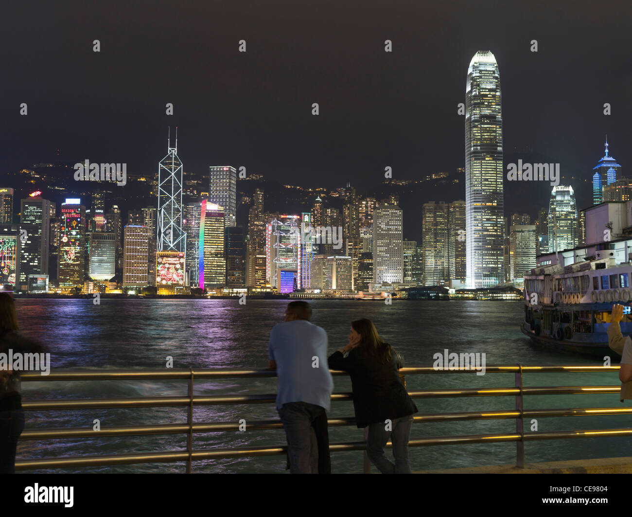 dh Hong Kong Harbour TSIM SHA TSUI HONG KONG Couple in Kowloon waterfront night lights people ...