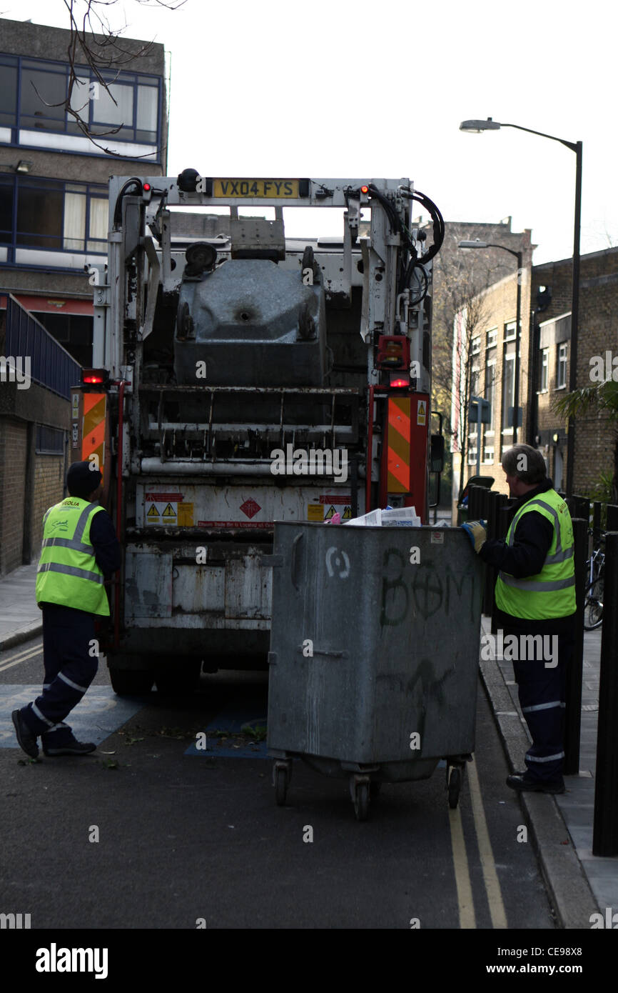 a refuse collector operating a dust cart and emptying a large wheelie ...