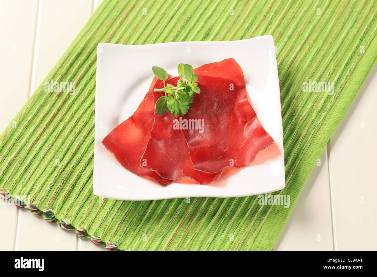 Thin slices of dried meat on a square plate Stock Photo - Alamy